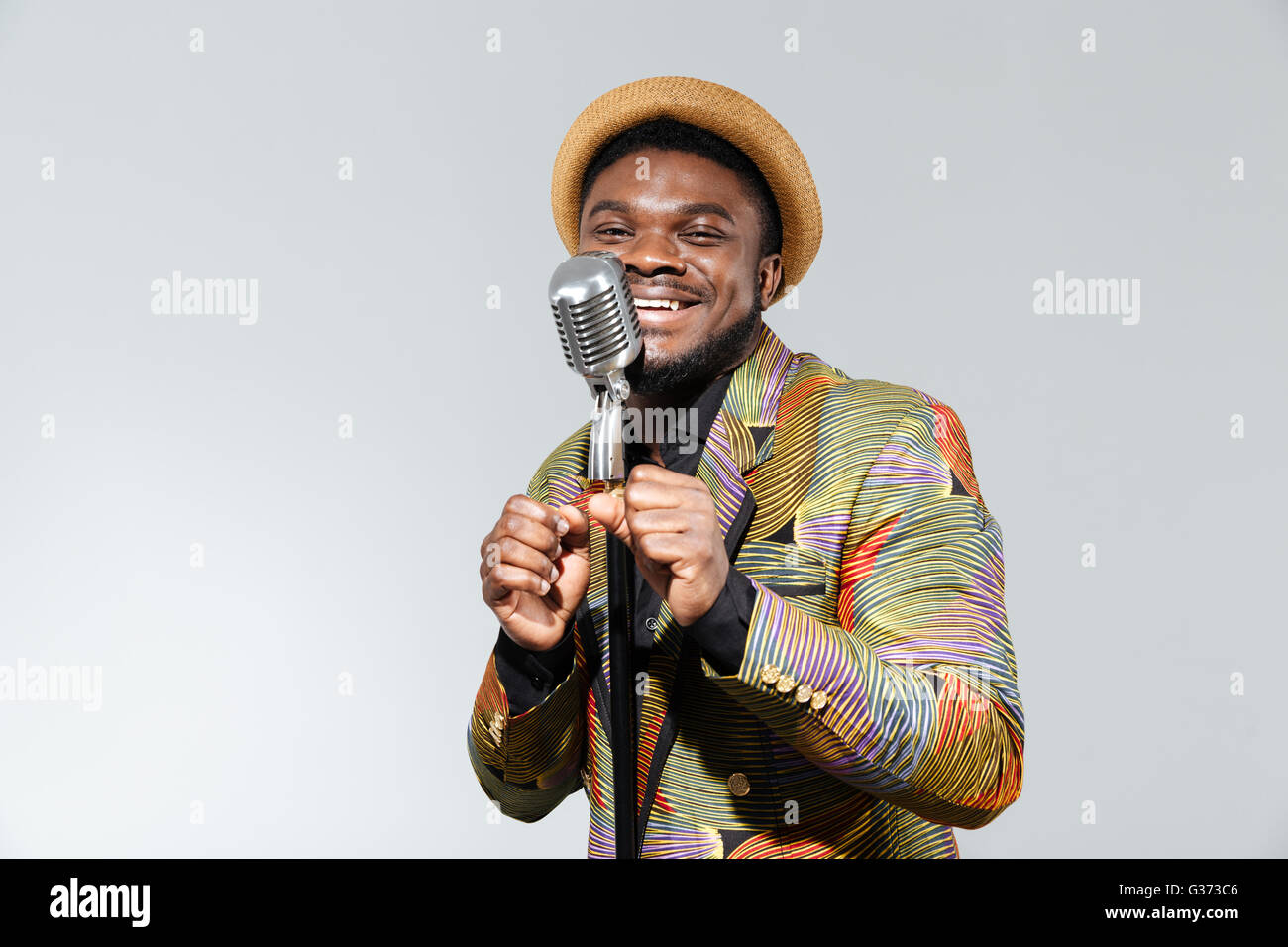 Stylish afro amerian man singing into vintage microphone isolated on a ...