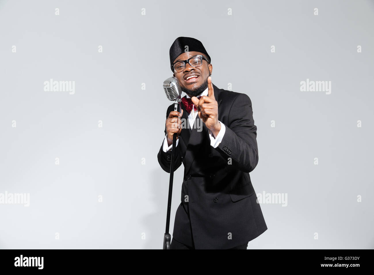 Fashion afro amerian man singing into vintage microphone isolated on a ...