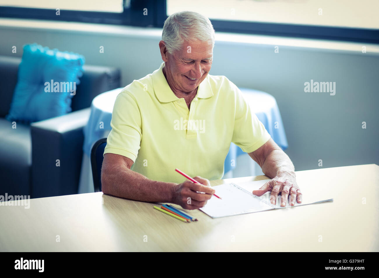 Senior man drawing with a colored pencil in drawing book Stock Photo ...