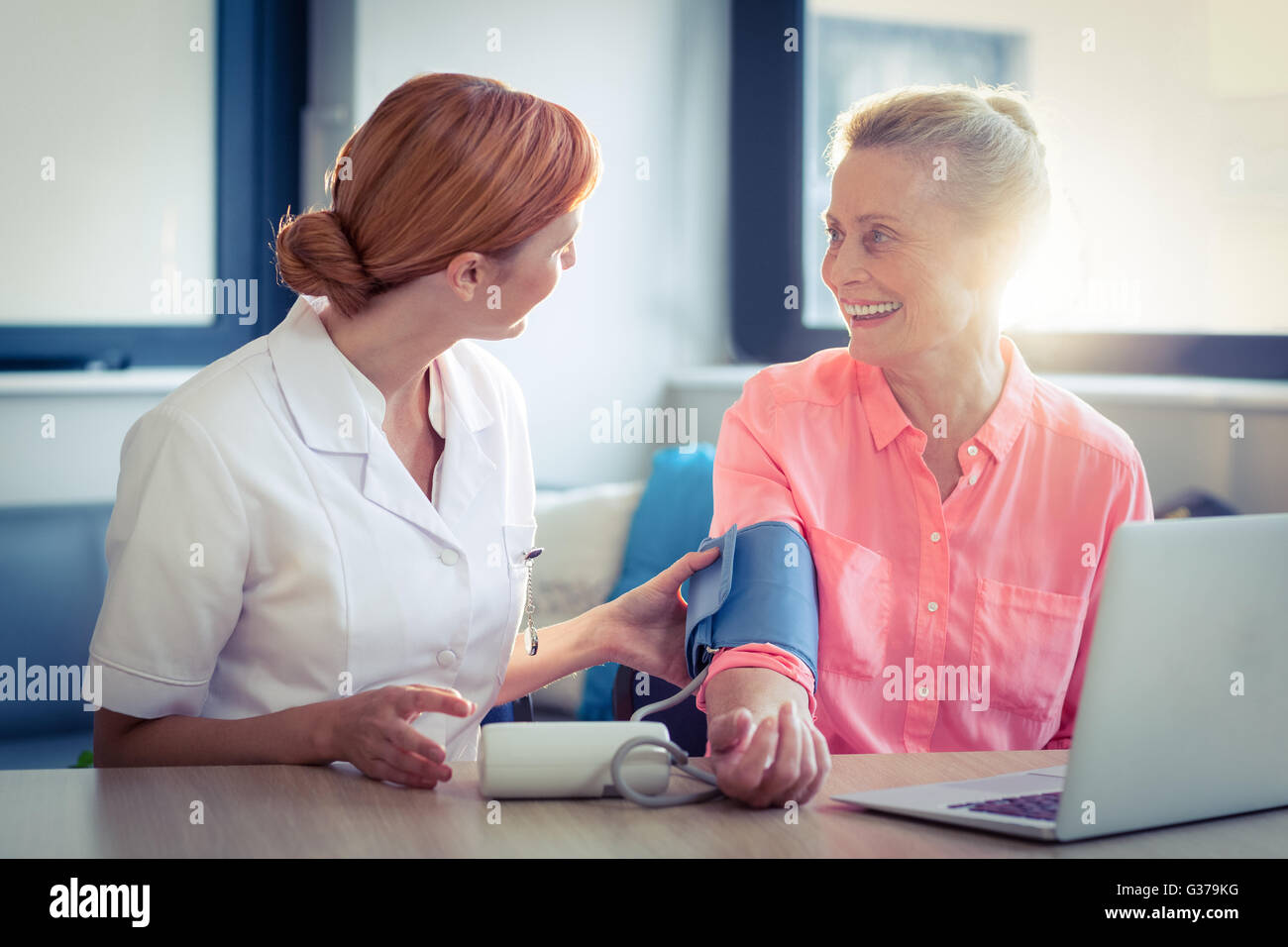Female nurse checking blood pressure of senior woman Stock Photo - Alamy
