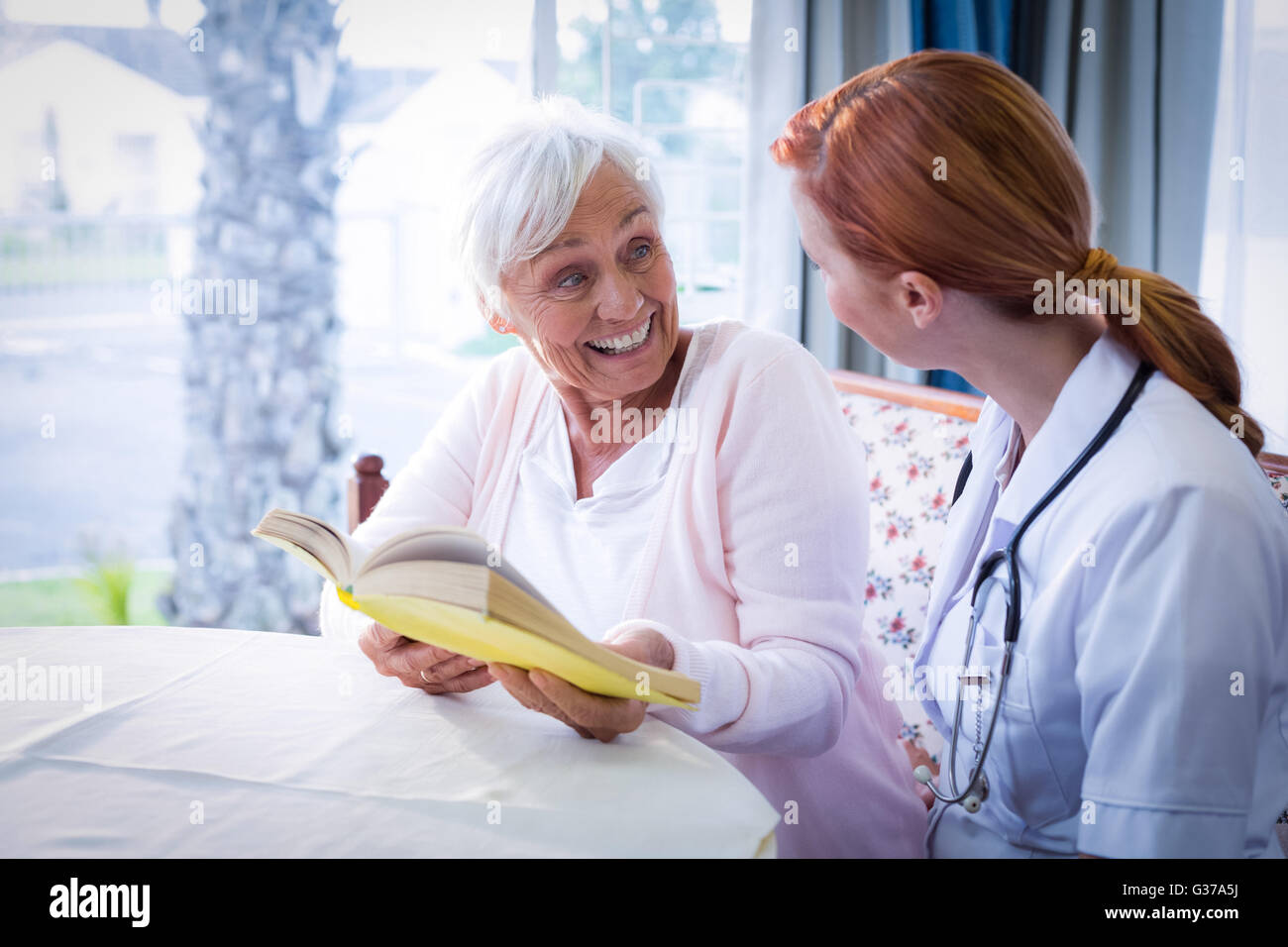Happy doctor and patient reading a book Stock Photo - Alamy