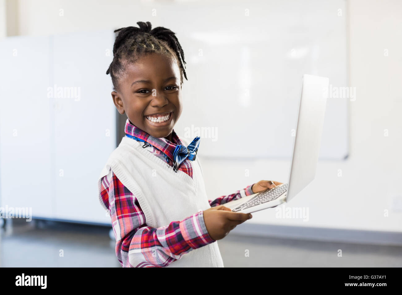 Portrait of happy schoolgirl using laptop in classroom Stock Photo - Alamy
