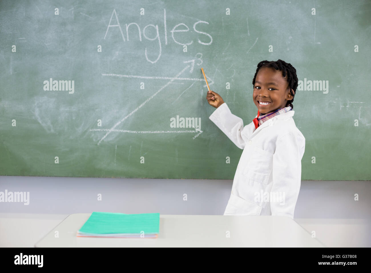 Portrait of schoolboy showing mathematics on chalkboard in classroom ...