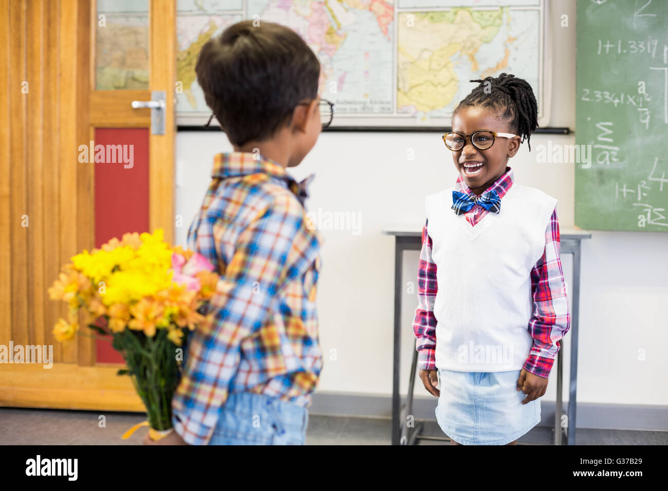 Schoolboy hiding flower behind his back in classroom Stock Photo - Alamy