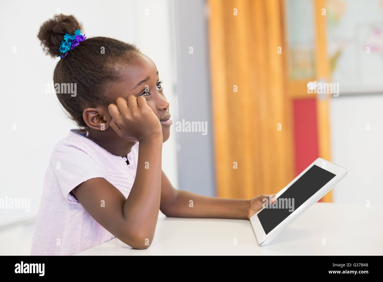Thoughtful schoolgirl with digital tablet in classroom Stock Photo - Alamy