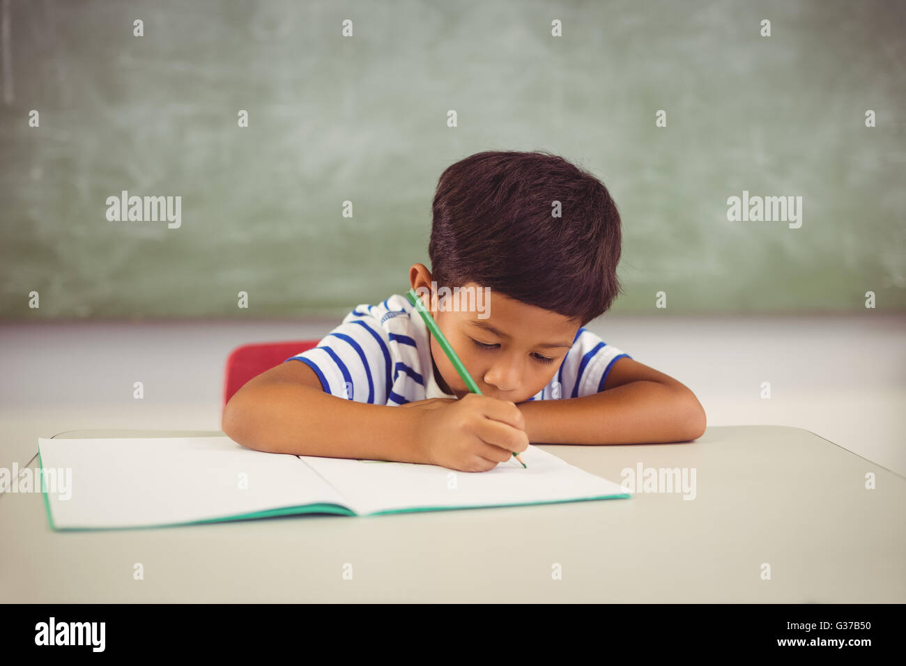 Boy doing homework in classroom Stock Photo - Alamy