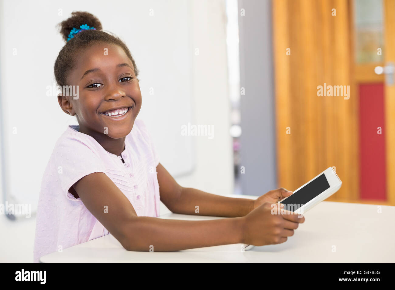 Smiling schoolgirl using digital tablet in classroom at school Stock ...