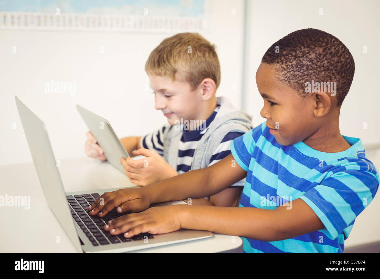 School kids using a laptop and digital tablet in classroom Stock Photo ...