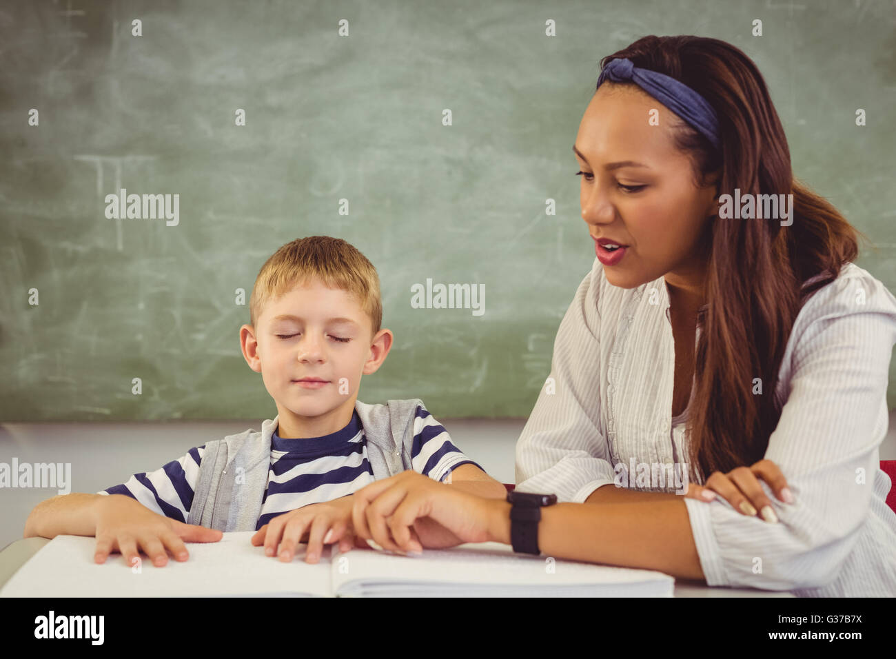 Teacher helping a boy with his homework in classroom Stock Photo - Alamy
