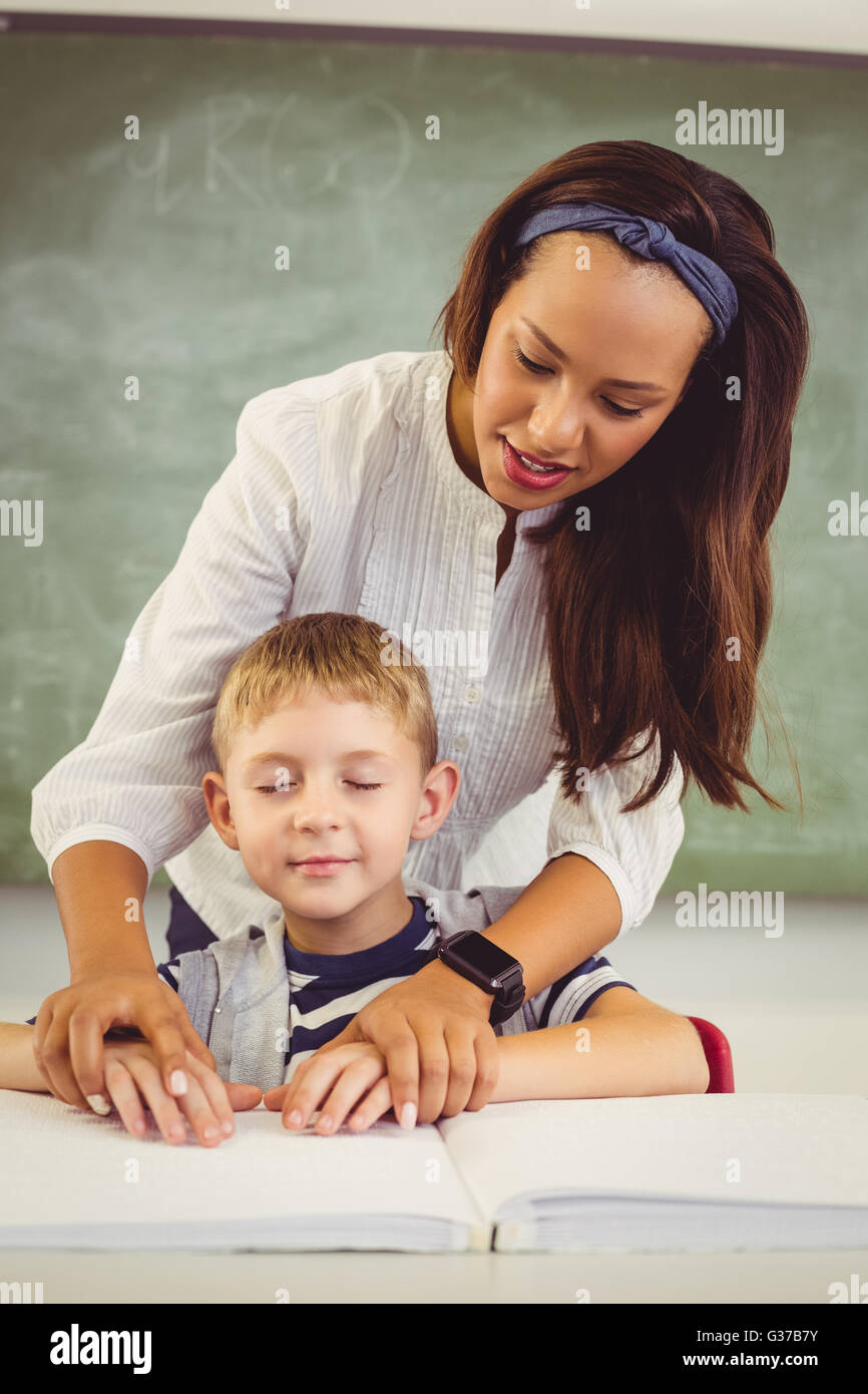 Teacher helping a boy with his homework in classroom Stock Photo - Alamy