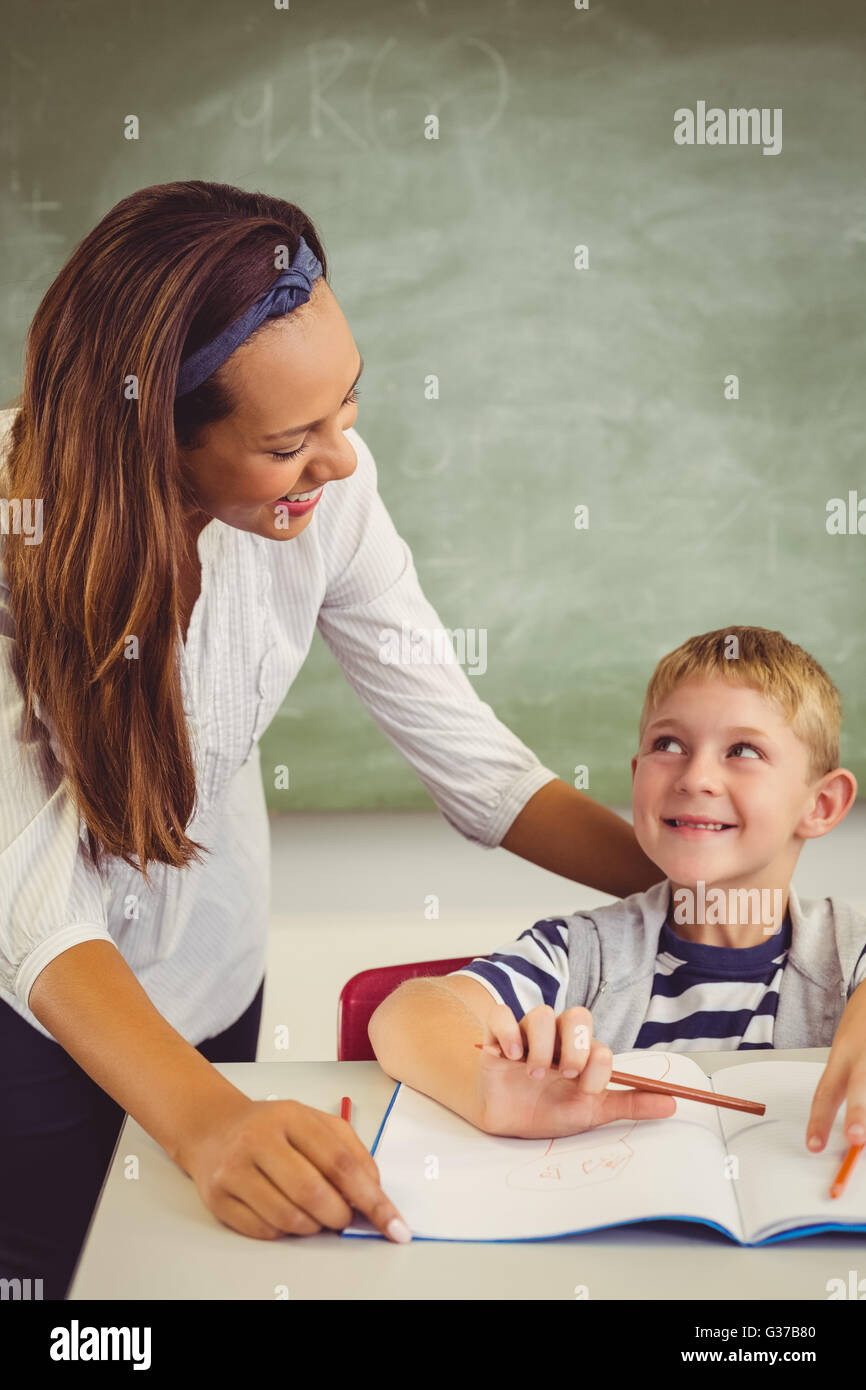 Teacher helping a boy with his homework in classroom Stock Photo - Alamy