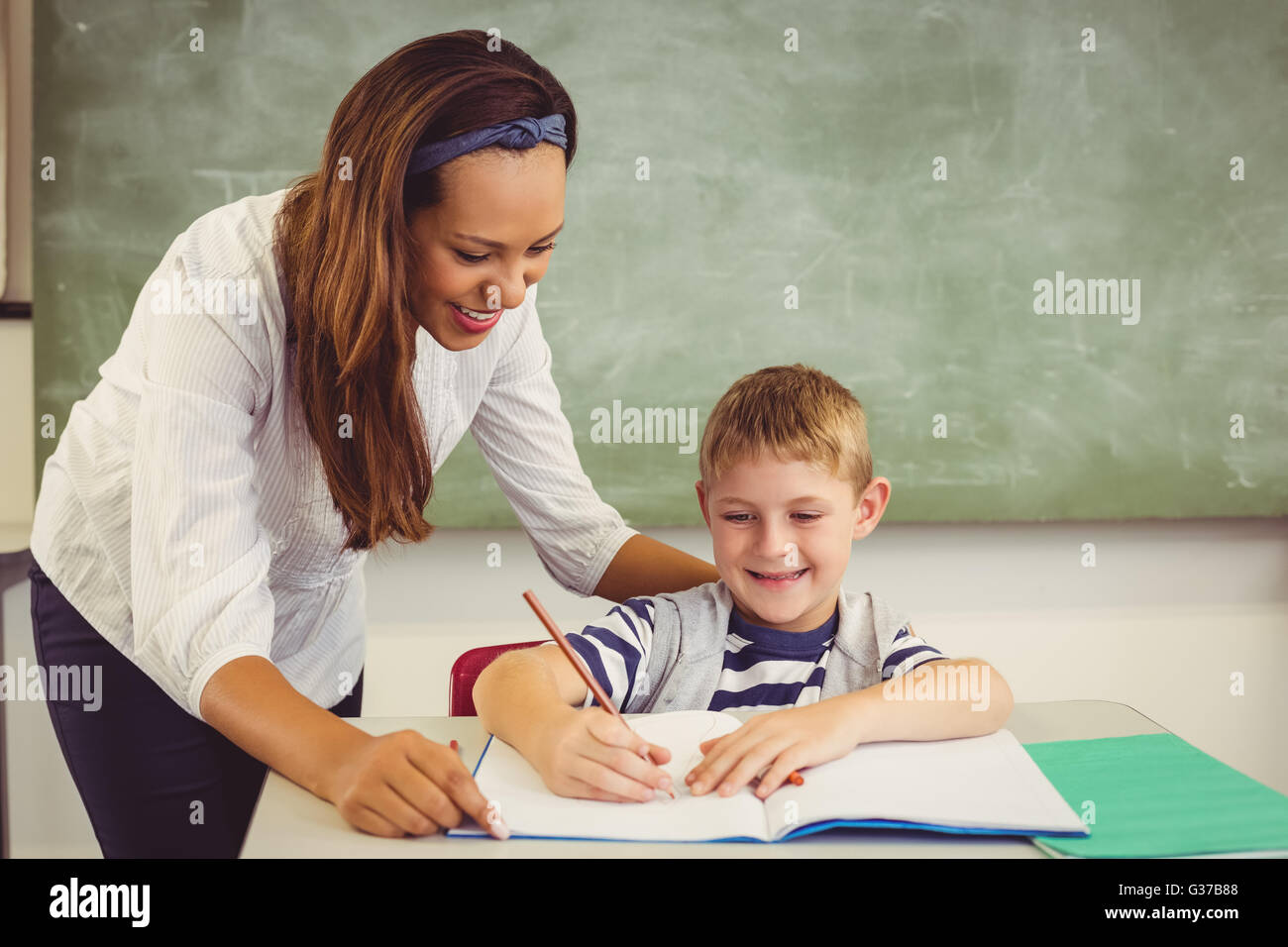 Teacher helping a boy with his homework in classroom Stock Photo - Alamy