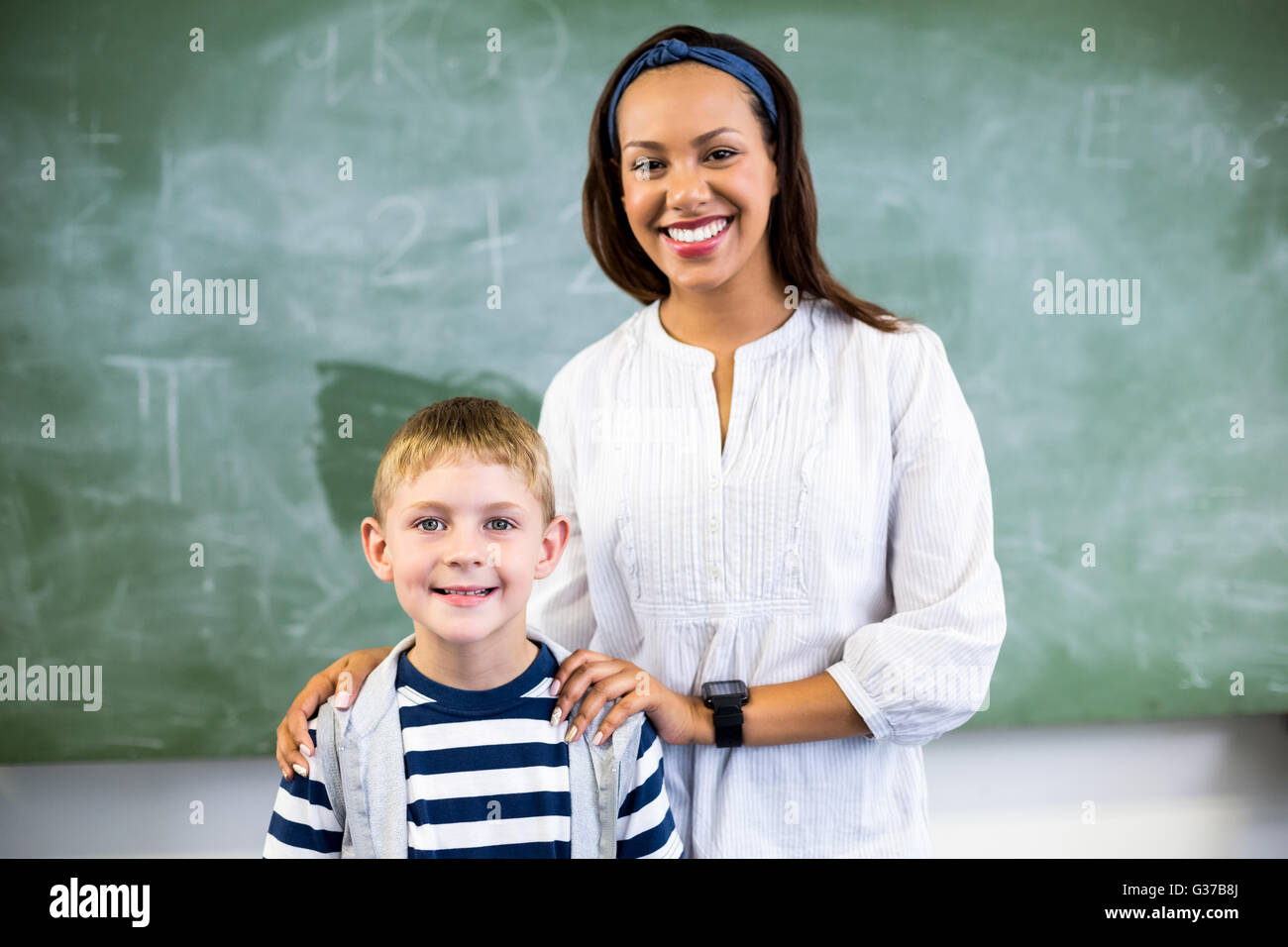 Portrait of smiling teacher and schoolboy standing in classroom Stock ...