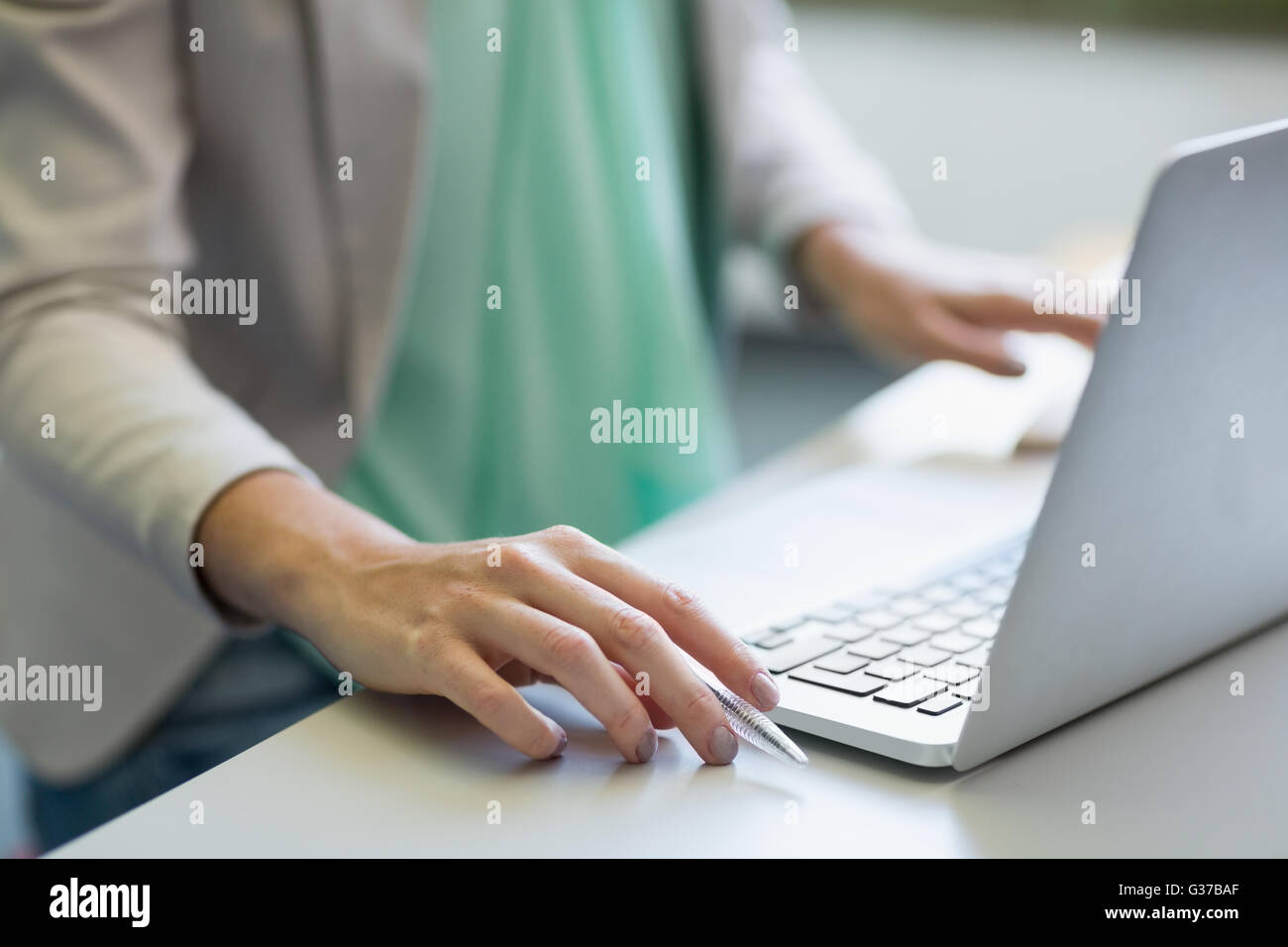 Teacher using laptop in library Stock Photo - Alamy