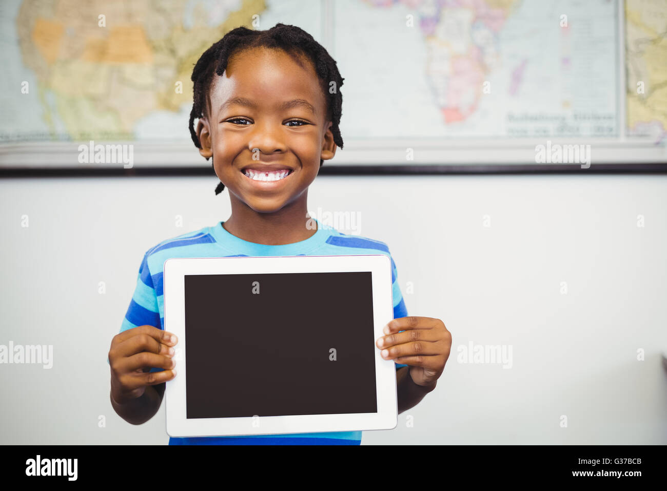Portrait of schoolboy showing digital tablet in classroom Stock Photo ...