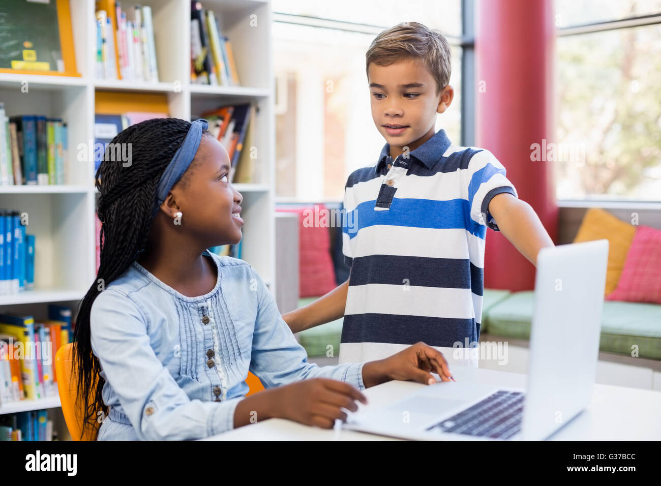 School kids using a laptop in library Stock Photo - Alamy