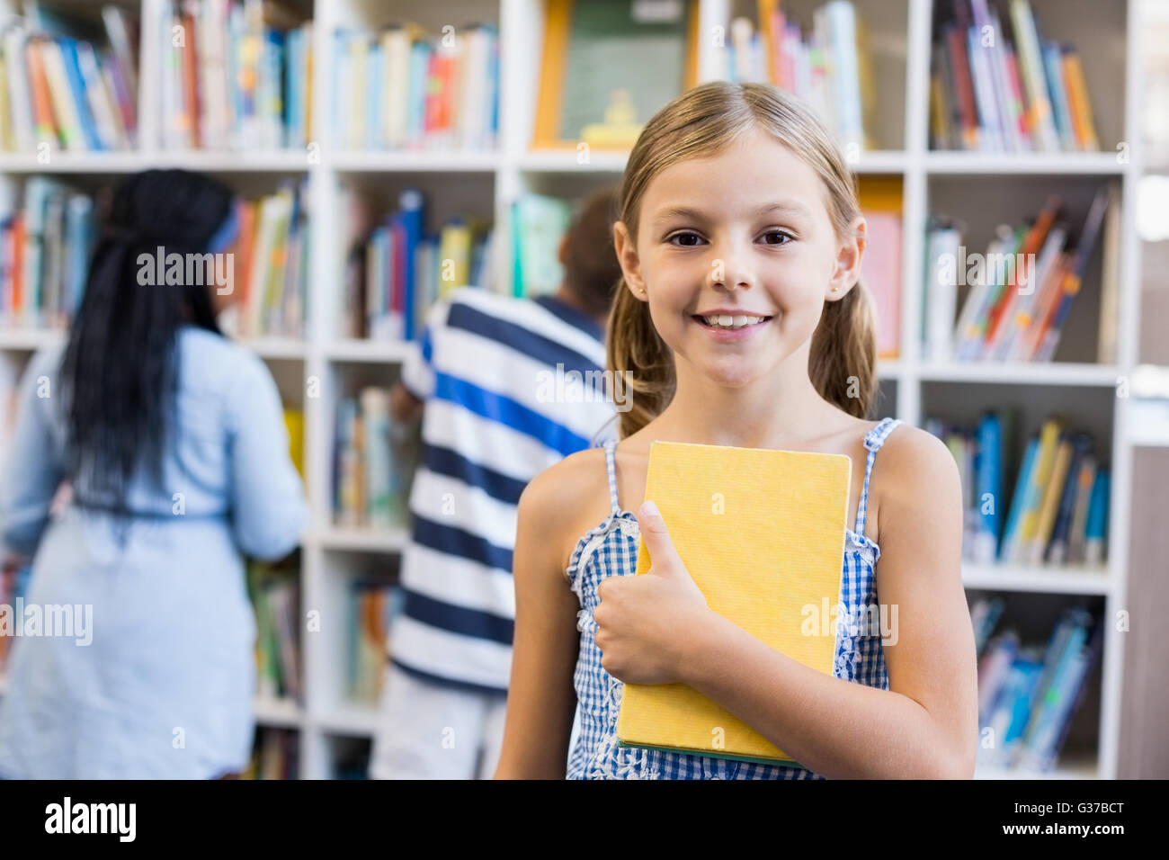 Girl holding a book in library Stock Photo - Alamy