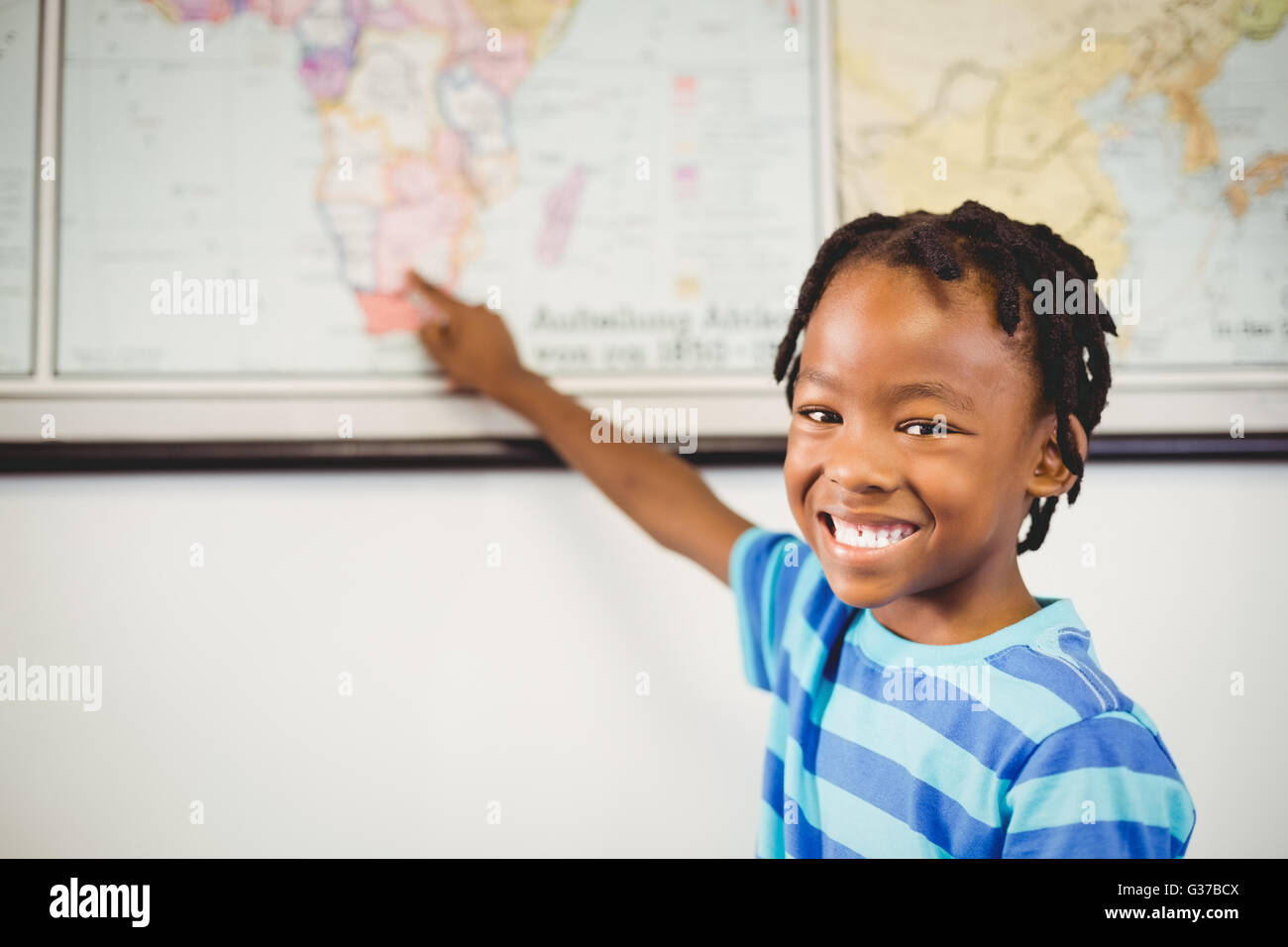 Portrait of schoolboy pointing on map in classroom Stock Photo - Alamy