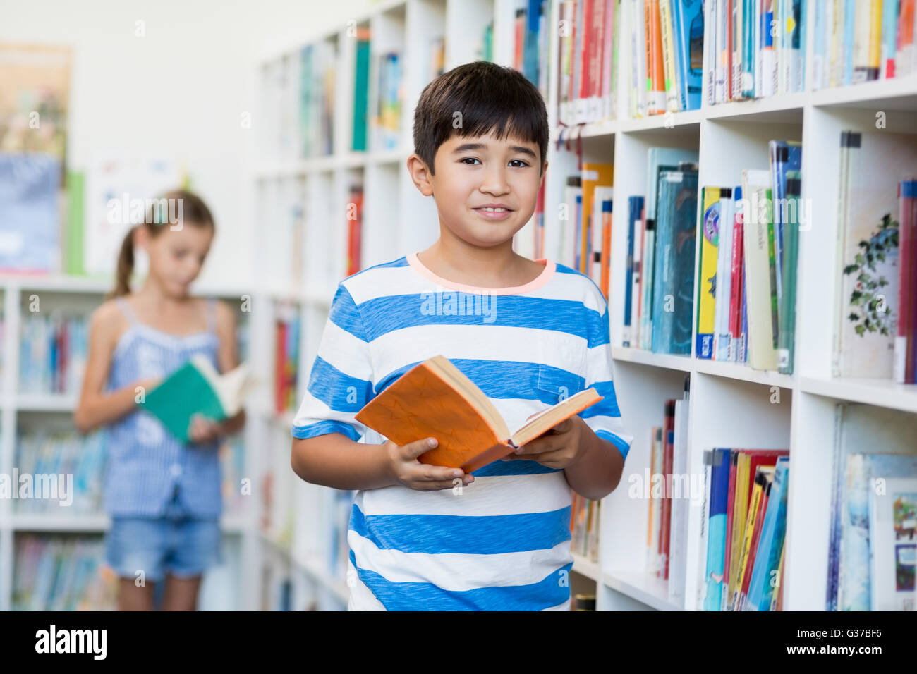 Boy holding a book in library Stock Photo - Alamy
