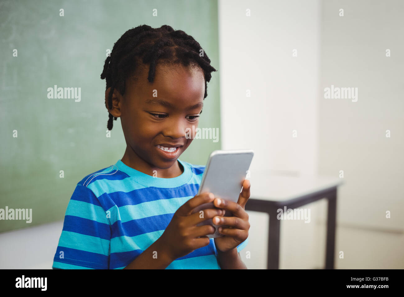 Schoolboy using mobile phone in classroom Stock Photo - Alamy