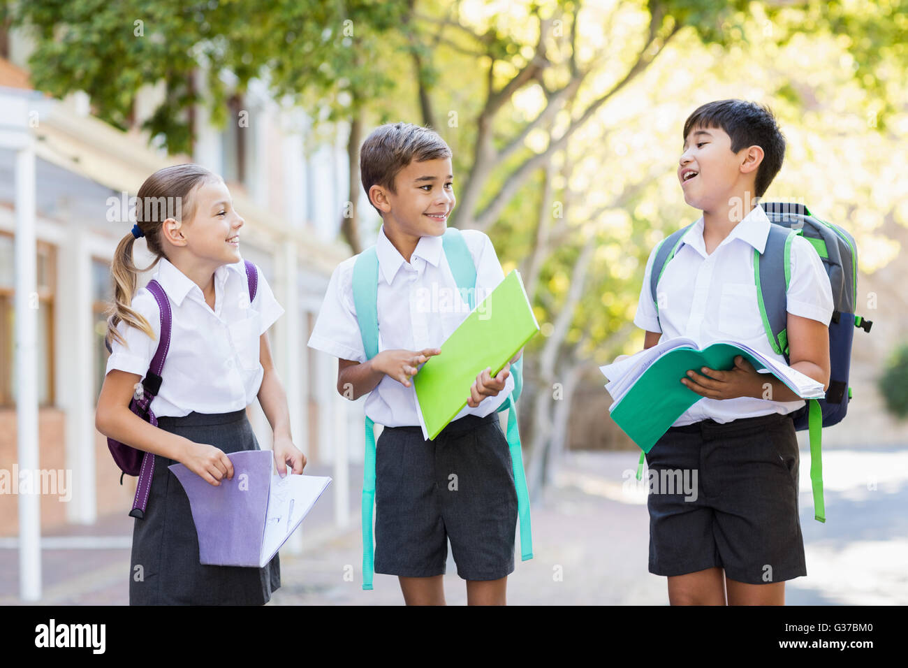 School kids talking to each other while reading books in campus Stock ...