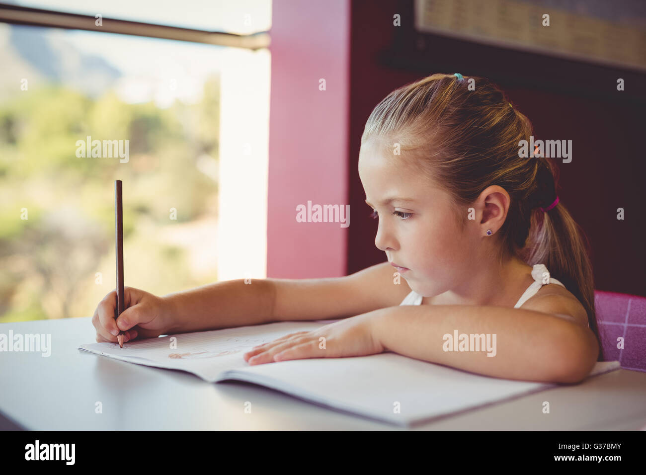 Girl doing homework in classroom Stock Photo - Alamy