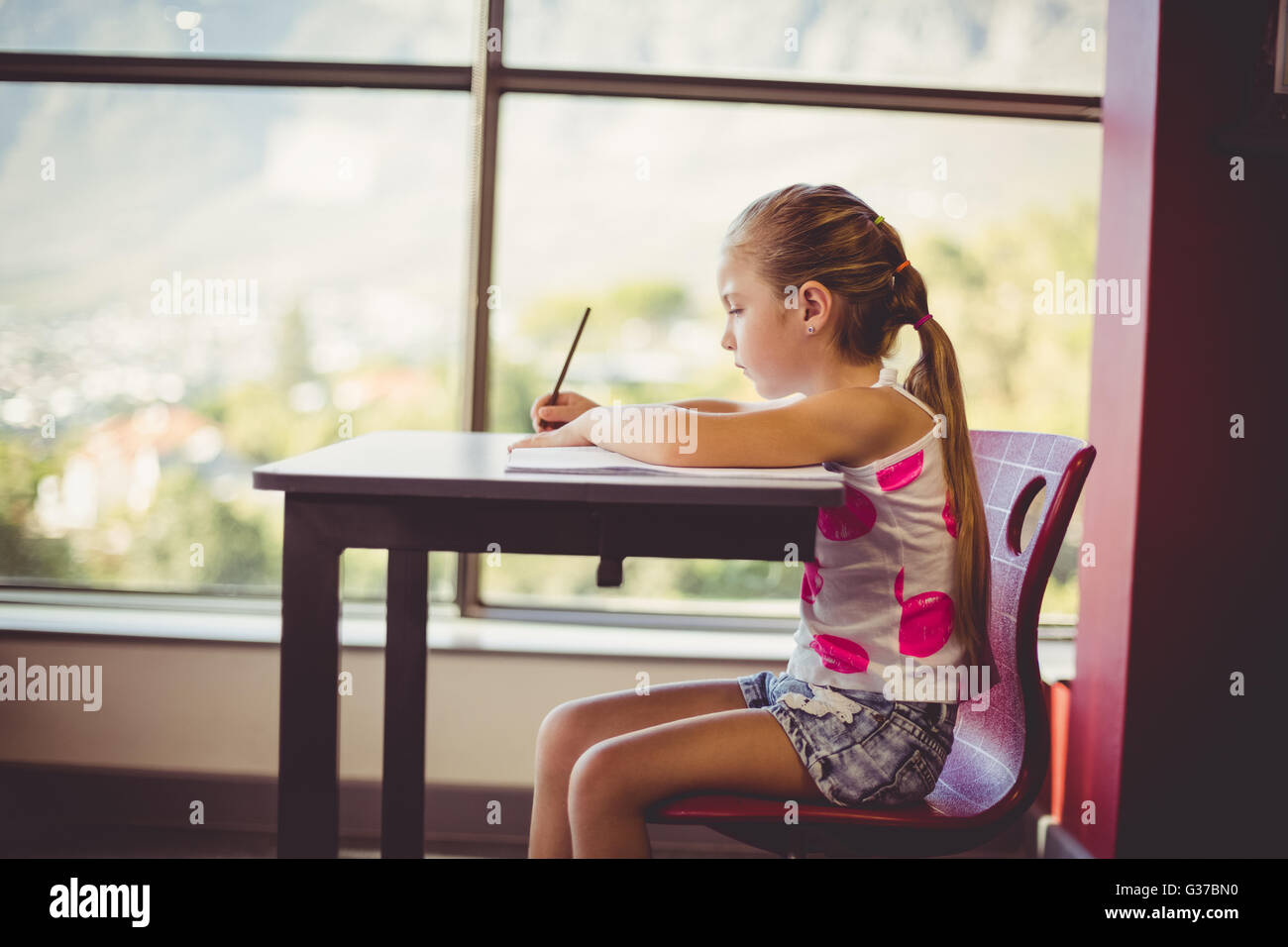Girl doing homework in classroom Stock Photo - Alamy