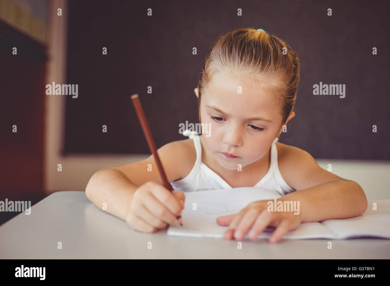 Girl doing homework in classroom Stock Photo - Alamy