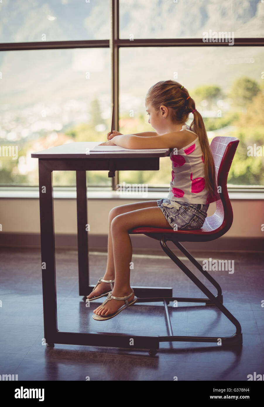 Girl doing homework in classroom Stock Photo - Alamy