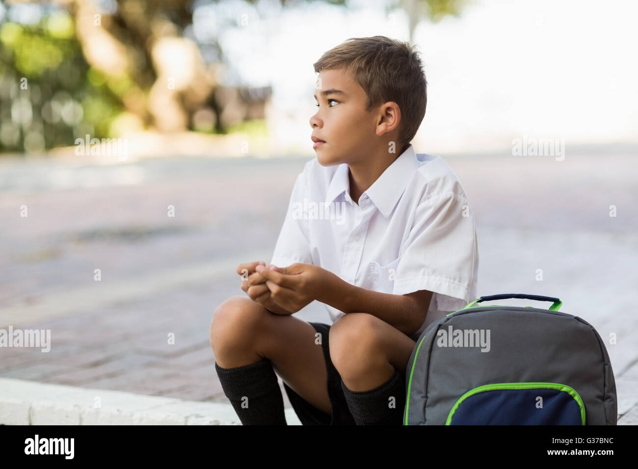 Thoughtful schoolboy sitting alone in campus Stock Photo - Alamy
