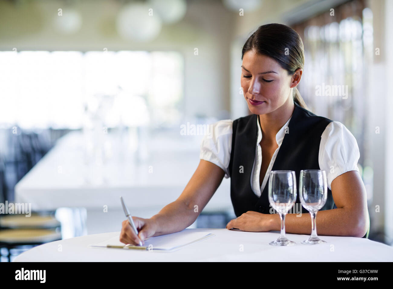 Waitress sitting at the table and writing notes Stock Photo - Alamy