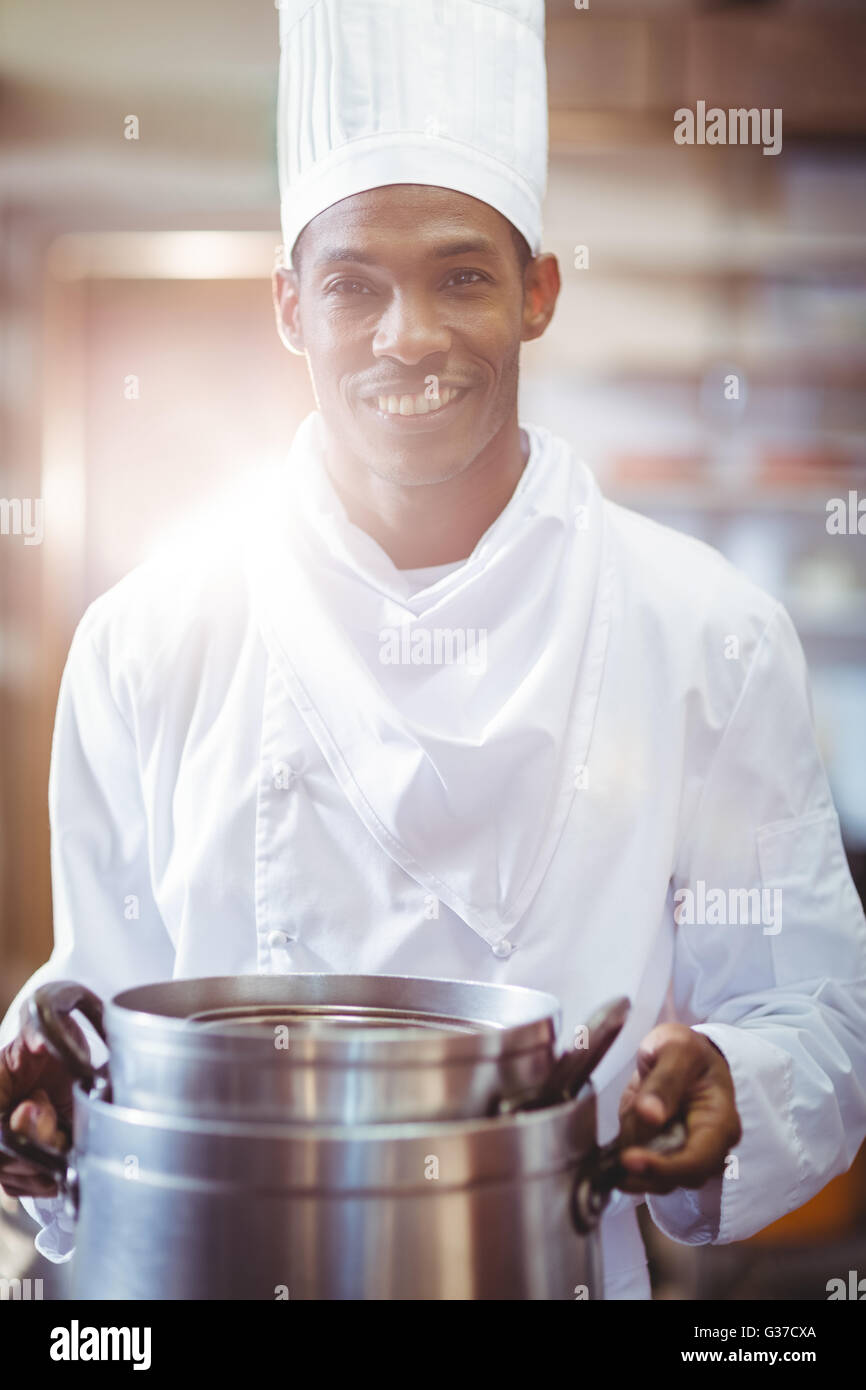 Smiling chef in kitchen holding cooking pot Stock Photo - Alamy