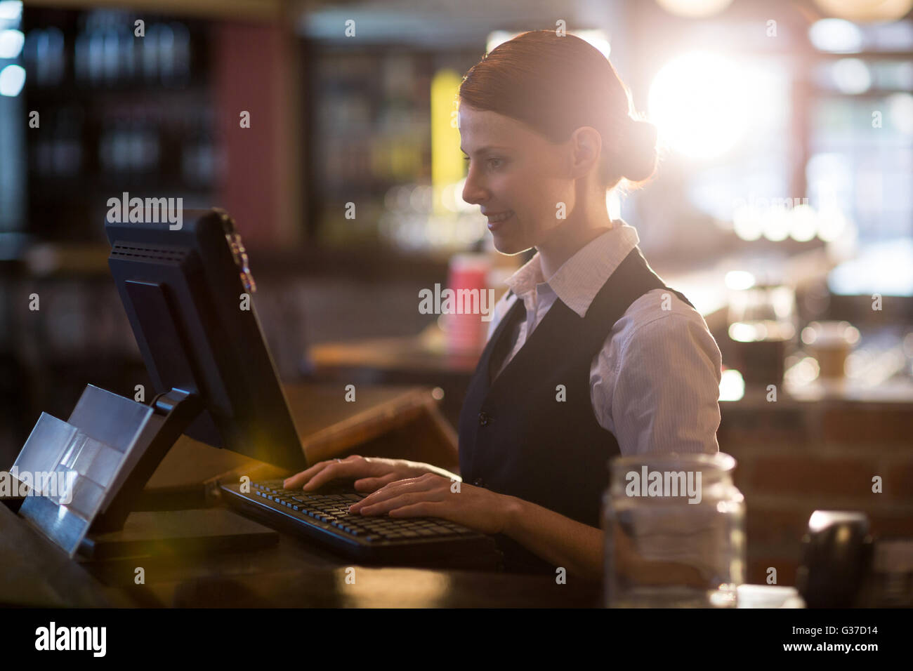 Waitress using a computer at counter Stock Photo - Alamy