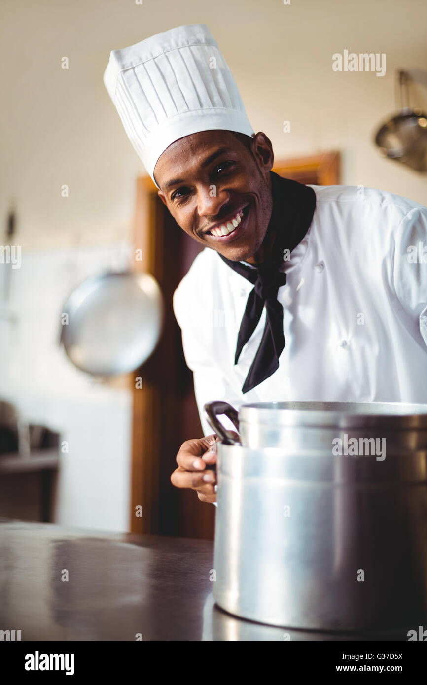 Smiling chef in kitchen holding cooking pot Stock Photo - Alamy