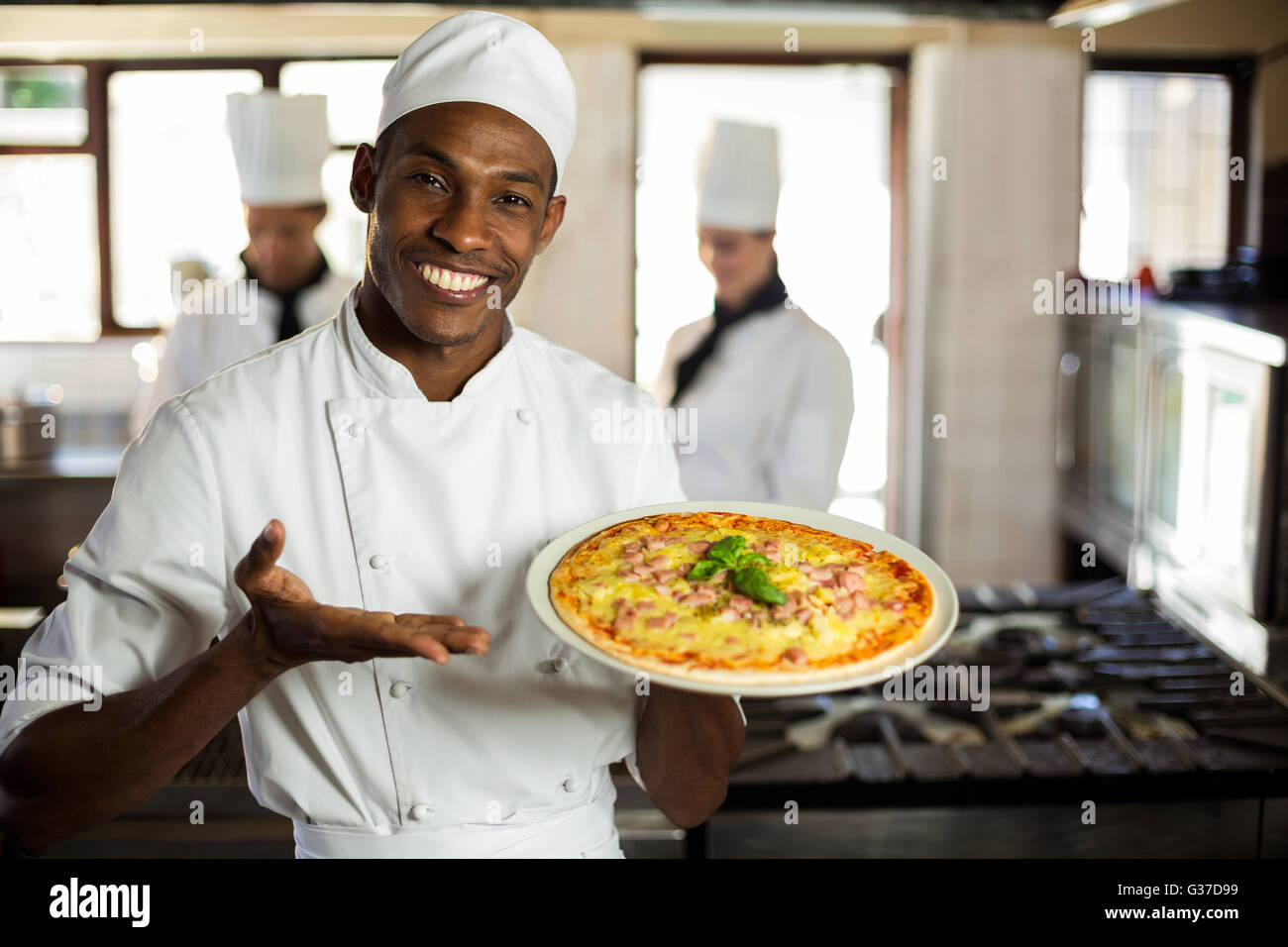 Portrait of smiling chef showing pizza Stock Photo - Alamy
