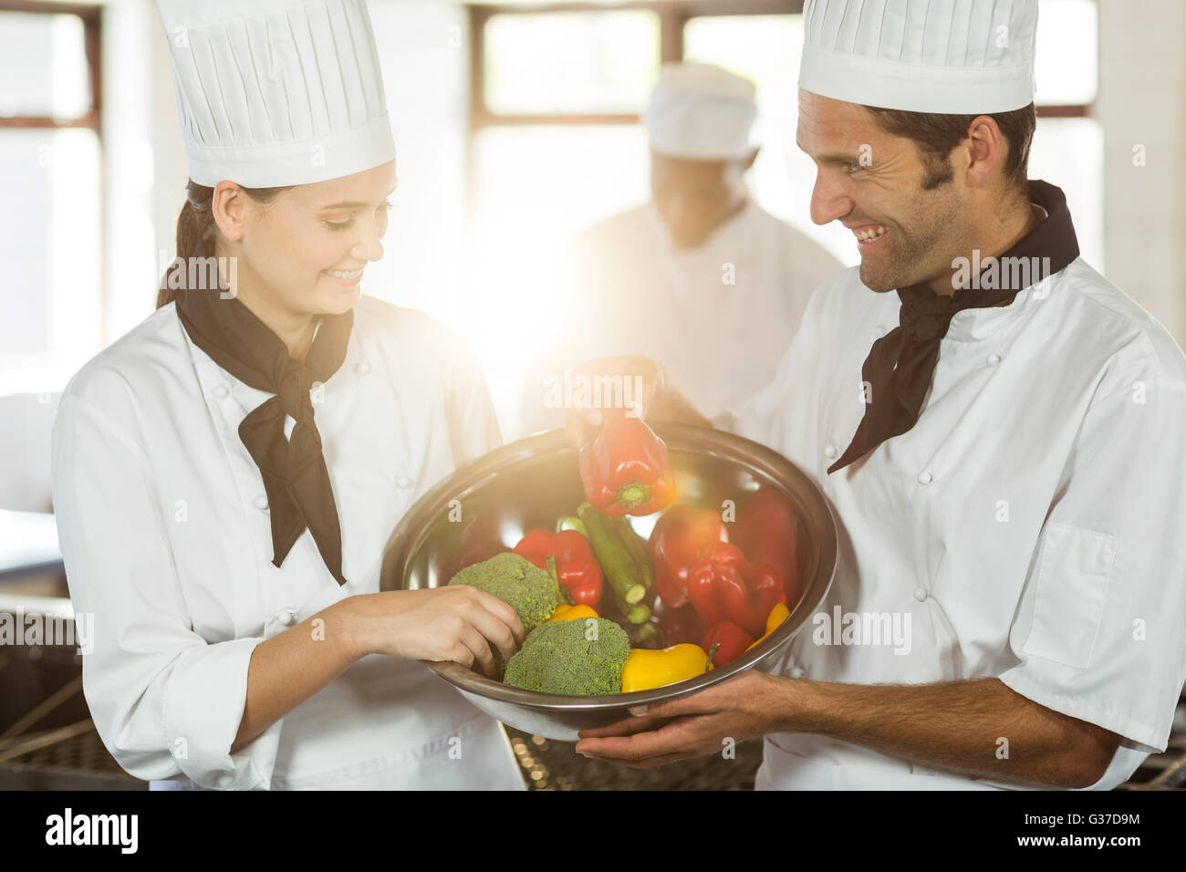 Two smiling chefs holding a bowl of vegetable Stock Photo - Alamy