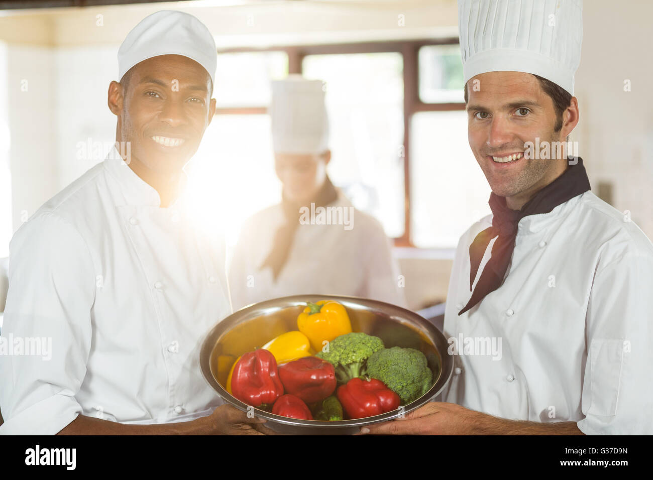 Portrait of two smiling chefs holding a bowl of vegetable Stock Photo ...