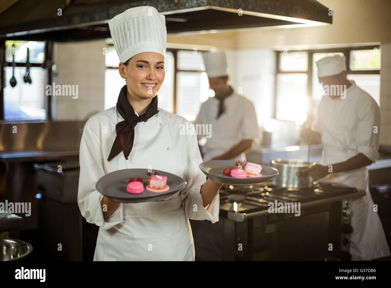 Portrait of smiling female chef presenting dessert plates Stock Photo ...