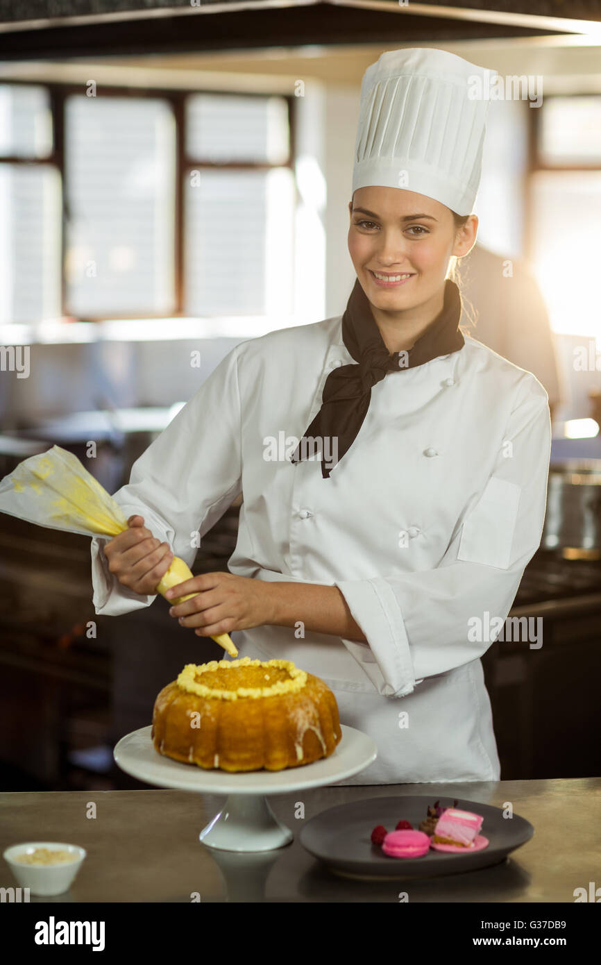 Portrait of female chef piping icing on cake Stock Photo - Alamy