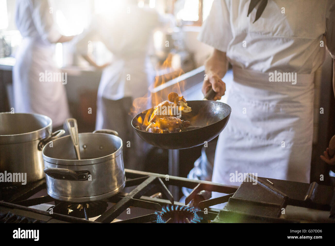 Mid section of chef cooking in kitchen stove Stock Photo - Alamy