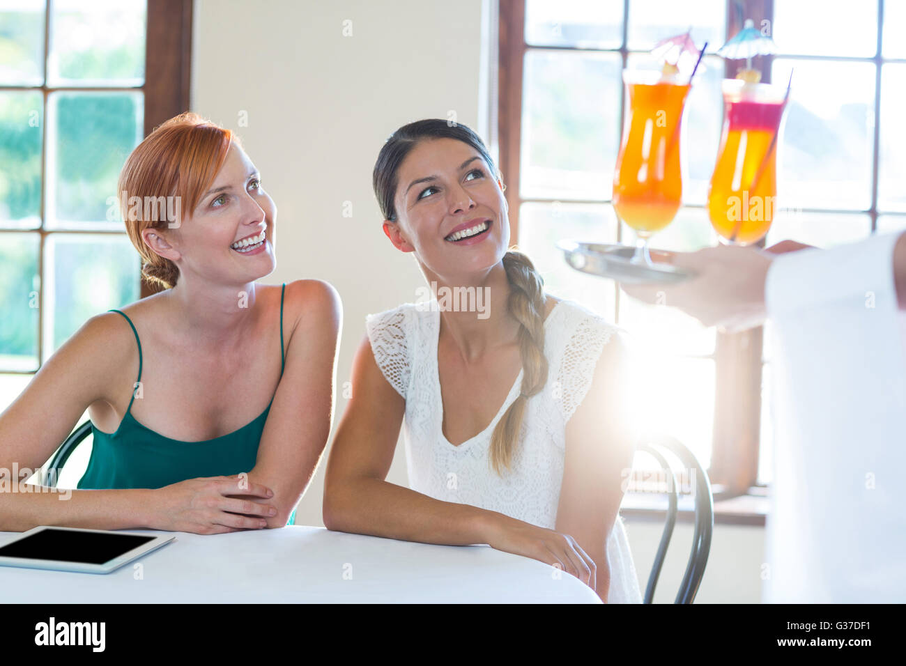 Waiter serving cocktail to women in restaurant Stock Photo - Alamy