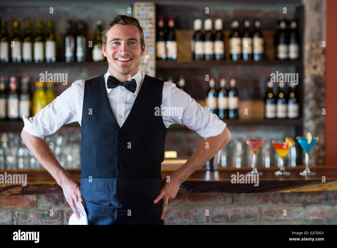 Portrait of confident waiter standing with hands on hip Stock Photo - Alamy