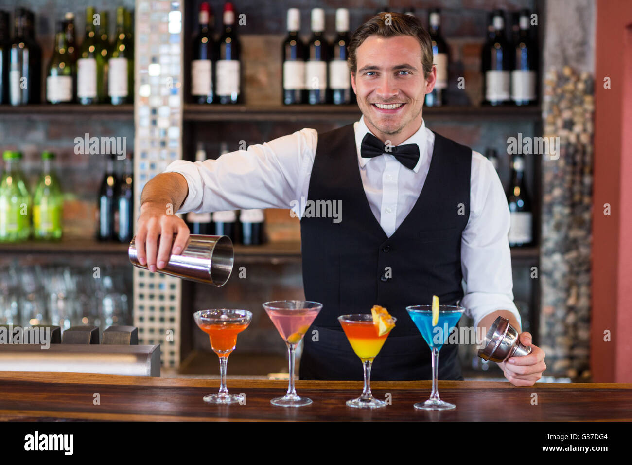 Portrait of bartender pouring a orange martini drink in the glass Stock ...
