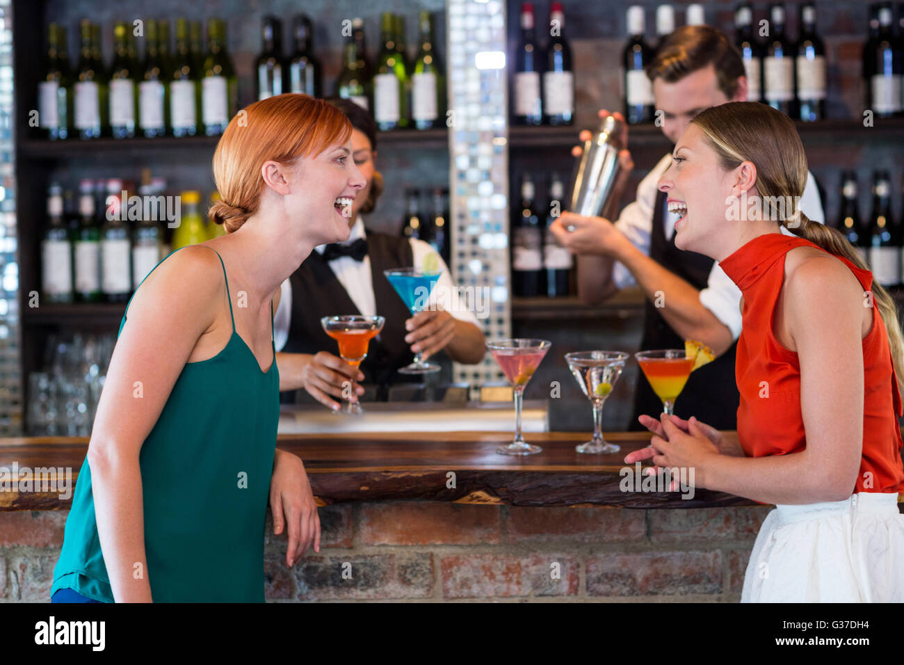 Friends standing at counter while bartender preparing a drink Stock ...