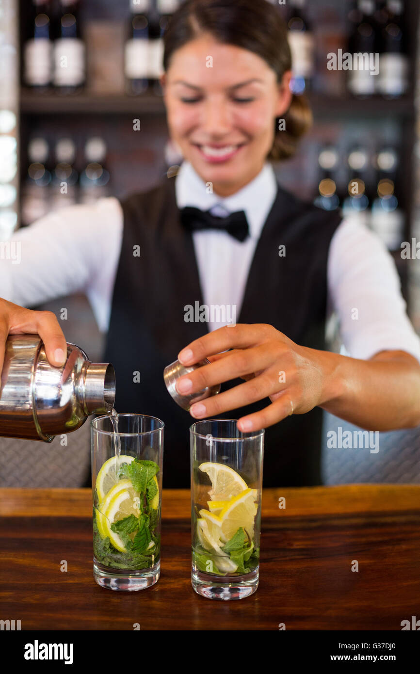 Bartender pouring a drink from a shaker to a glass on bar counter Stock Photo - Alamy