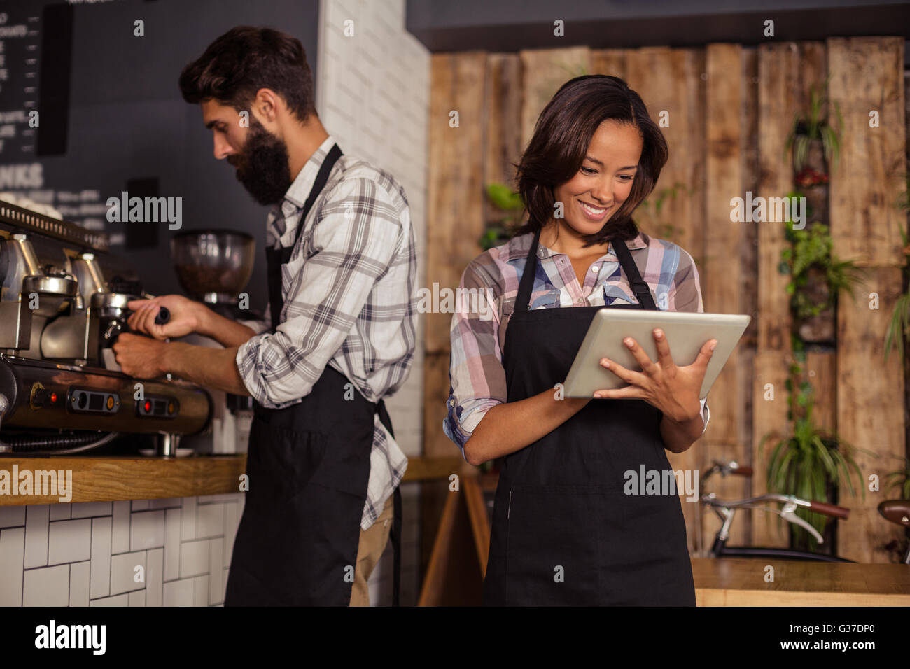 Waitress using a tablet computer and waiter with coffee machine Stock ...