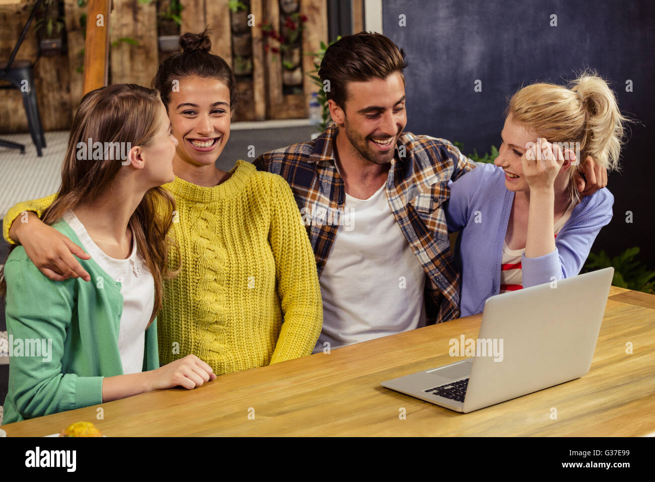 Smiling friends using laptop together Stock Photo - Alamy