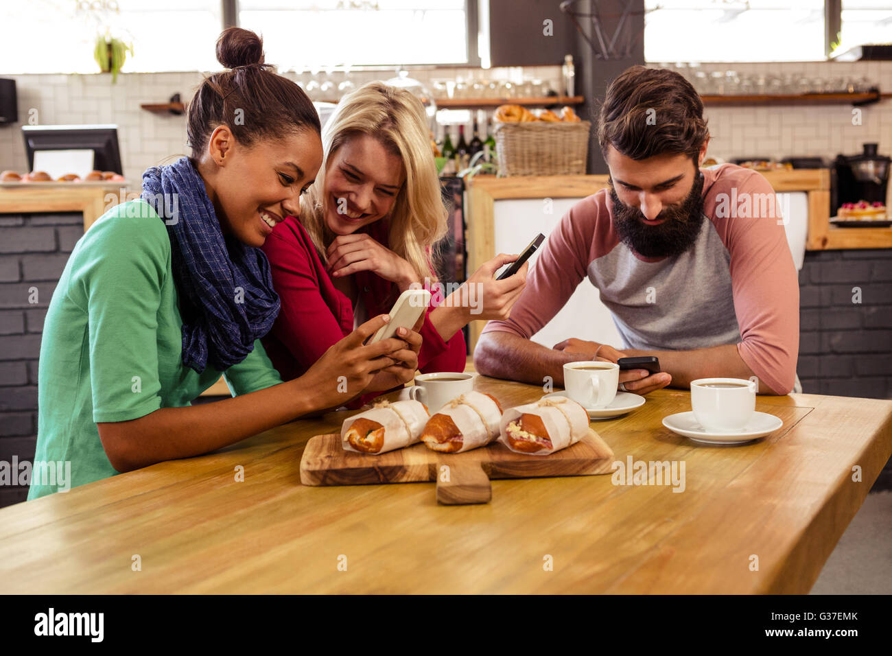 Friends using smartphones sitting Stock Photo - Alamy