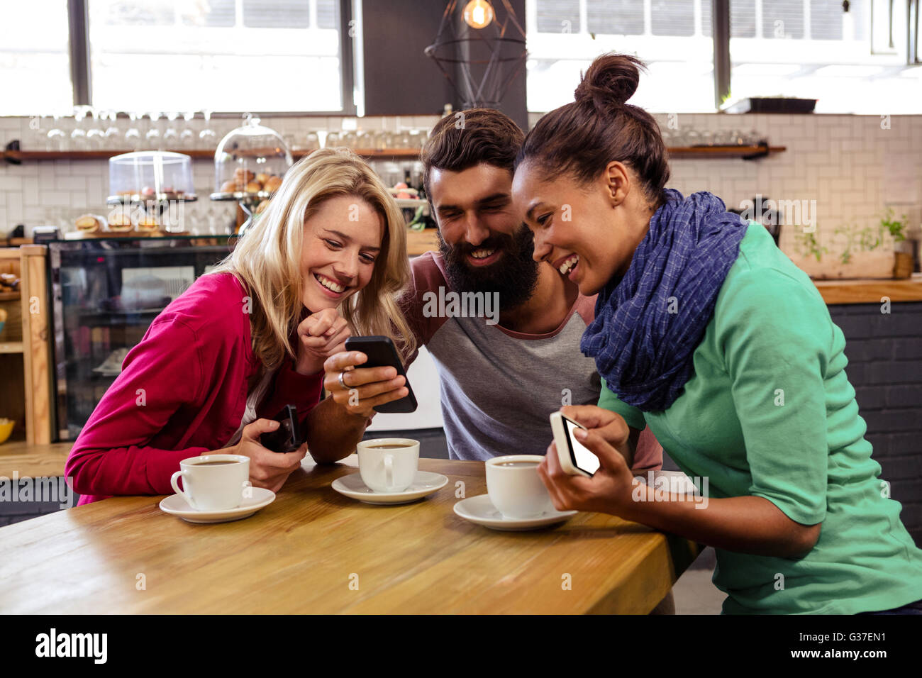 Friends using smartphones sitting Stock Photo - Alamy