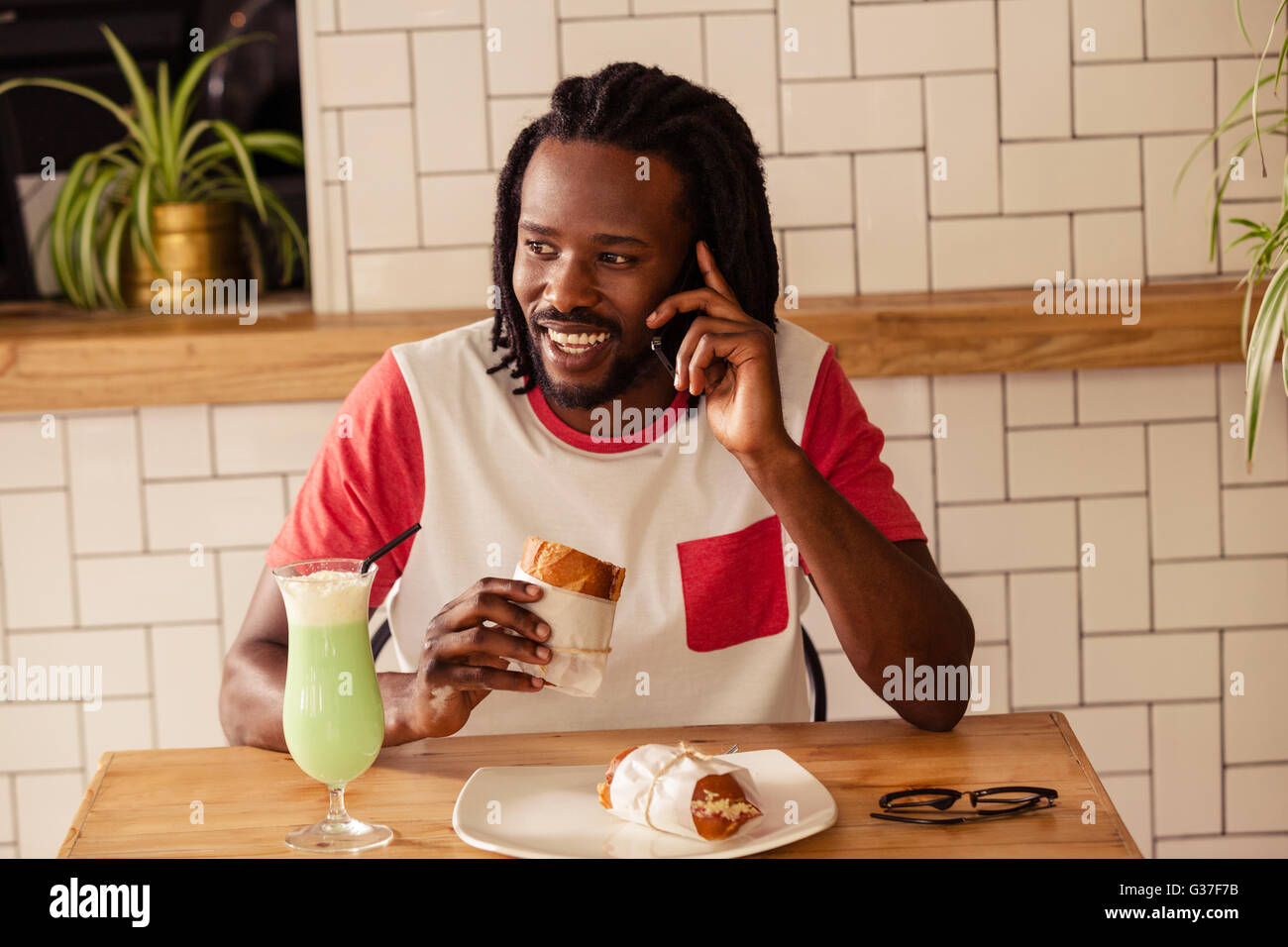 Portrait of hipster man on the phone while eating Stock Photo - Alamy